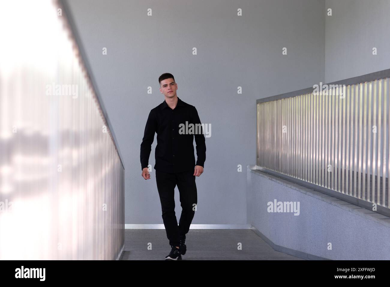 Young businessman going along long office corridor with window corridor ...