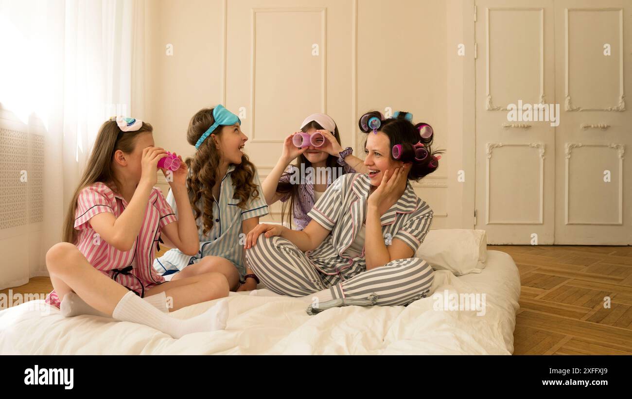 Girls enjoying a playful moment with hair rollers and pajamas. Family ...