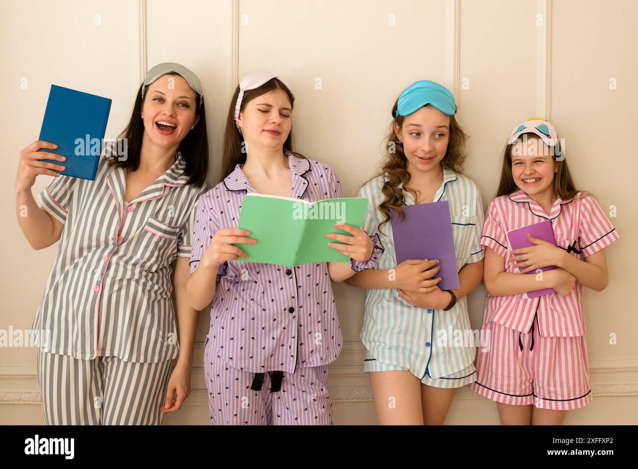 A woman and three girls in striped pajamas holding books, laughing and ...