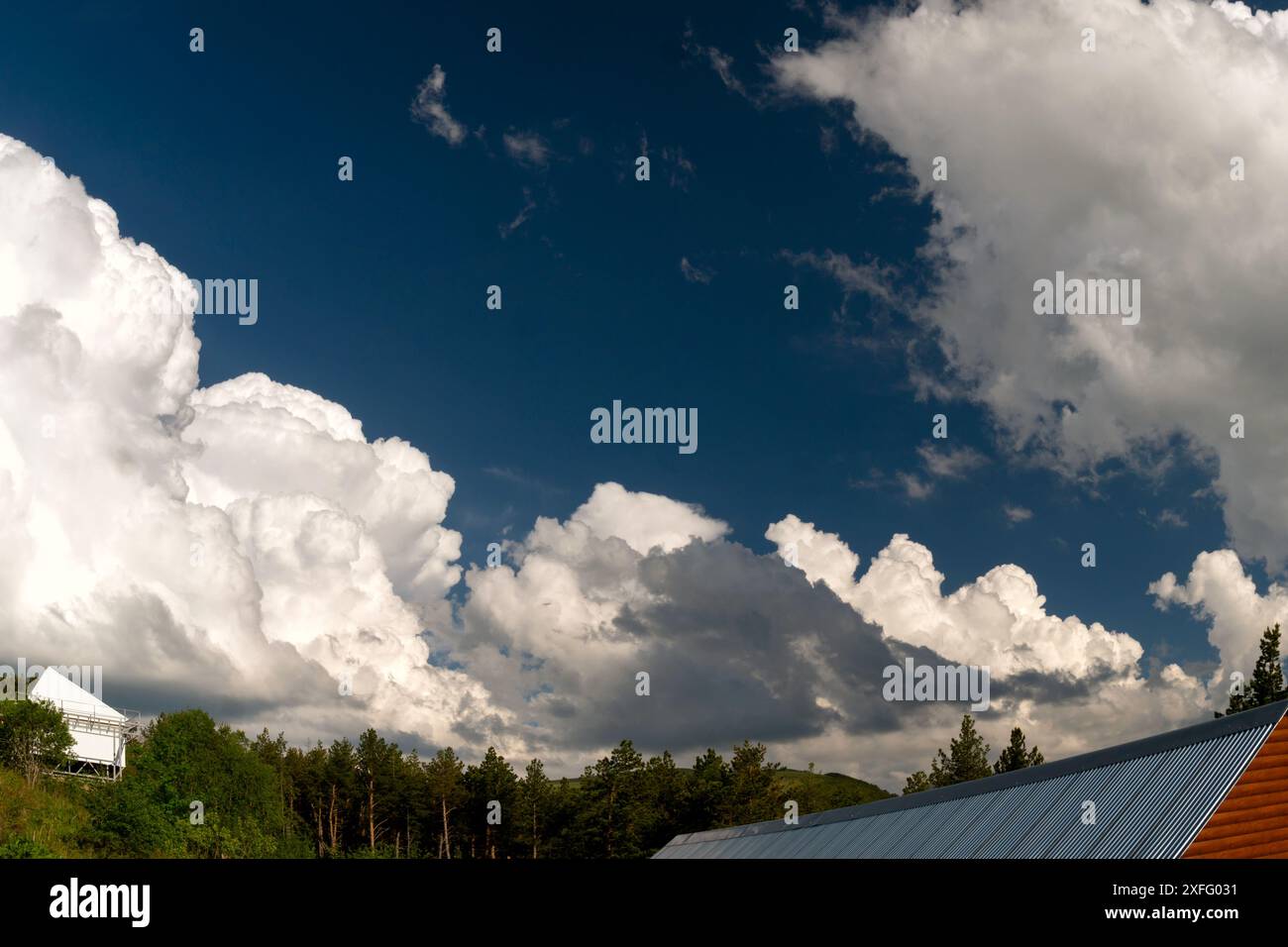 Expansive sky with cumulus clouds over rooftops and a wooded area Stock ...