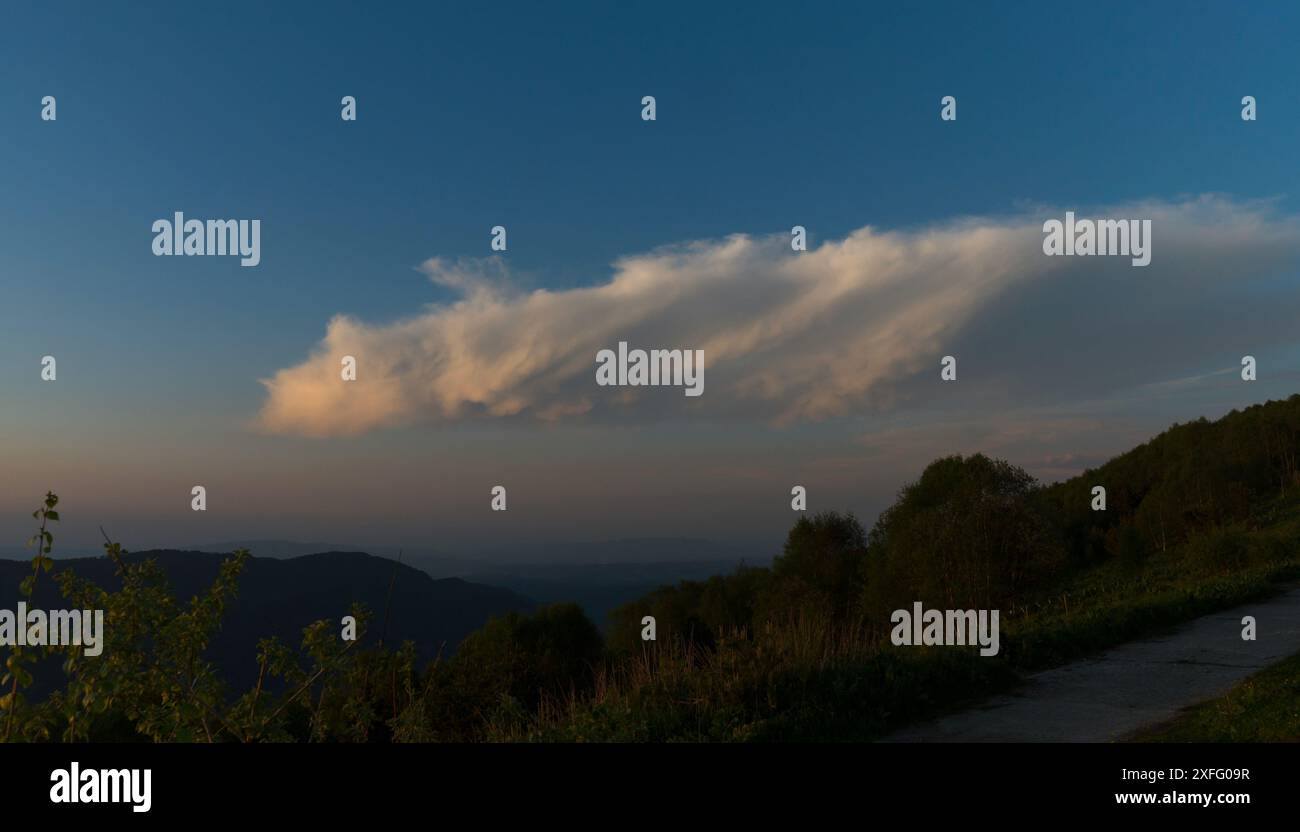 Sunset sky with a single cloud over a mountainous landscape Stock Photo ...