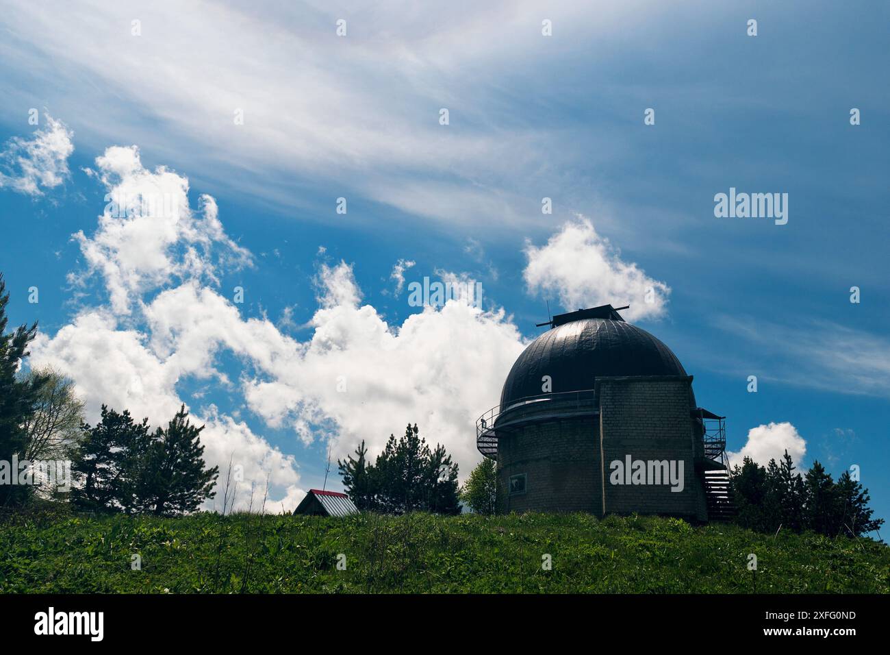 Brick observatory dome on a grassy hill with blue sky and clouds Stock ...