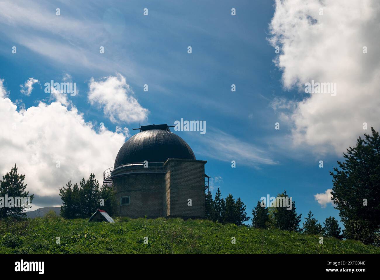 Brick observatory dome on grassy hill with cloudy sky. Space for text ...
