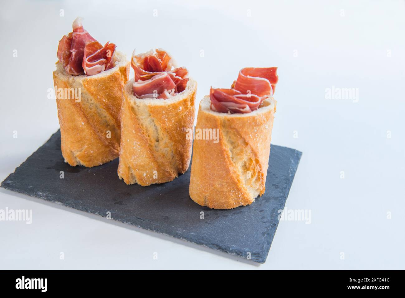 Spanish tapa: rolls of bread stuffed with Iberian ham Stock Photo - Alamy