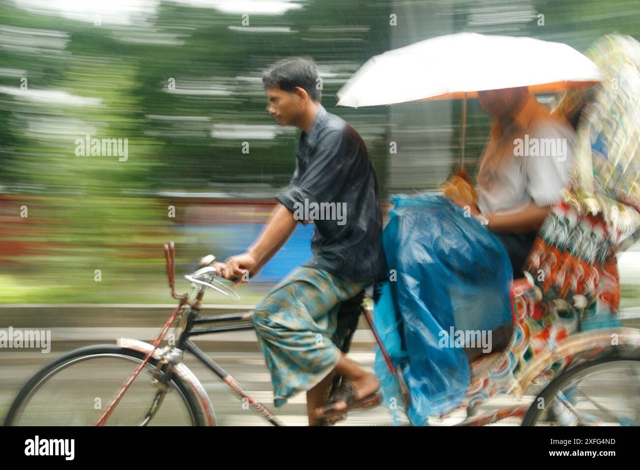 Commuters pass through the street of Dhaka University during heavy rain ...