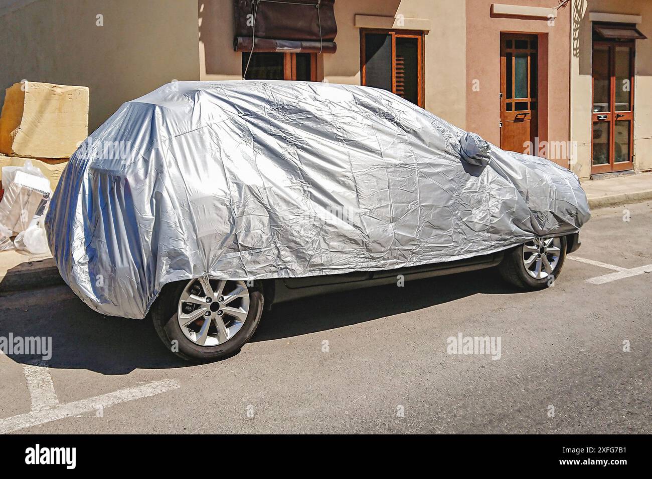 Vehicle parked on the street, fully covered with a protective silver ...