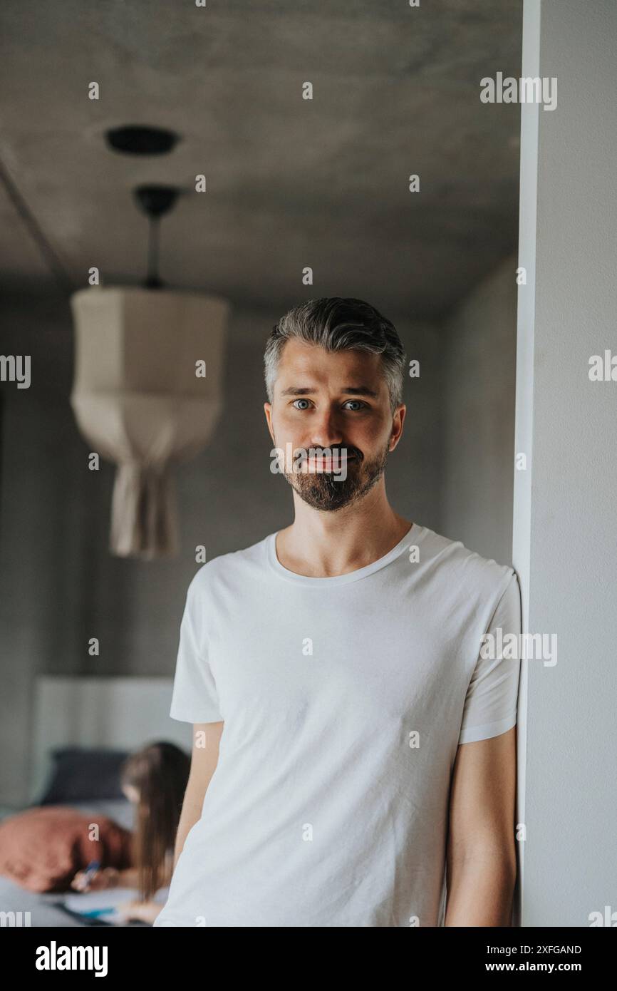 Portrait of smiling man with beard leaning on wall at home Stock Photo ...