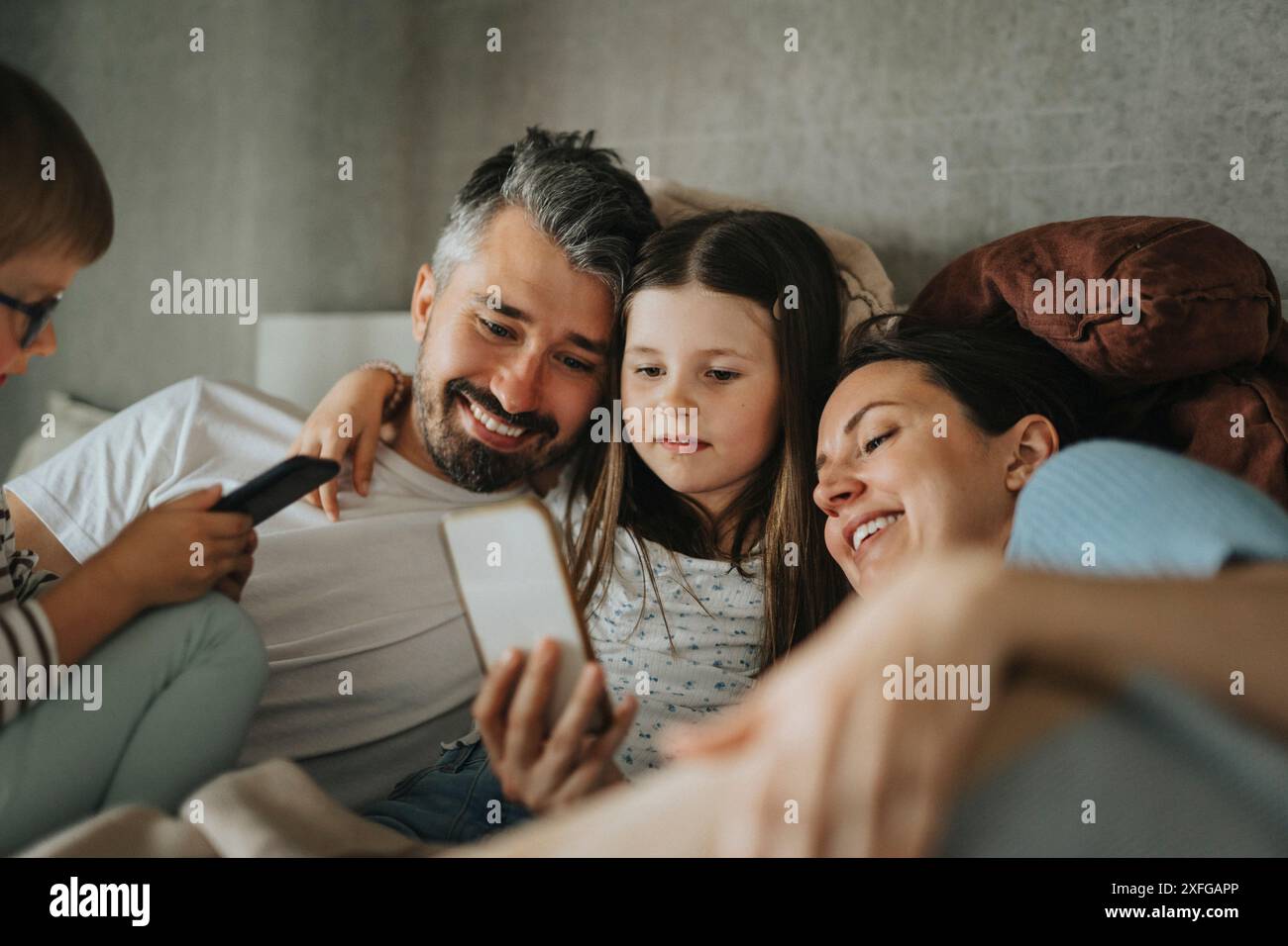 Happy family enjoying watching smart phone at home Stock Photo - Alamy