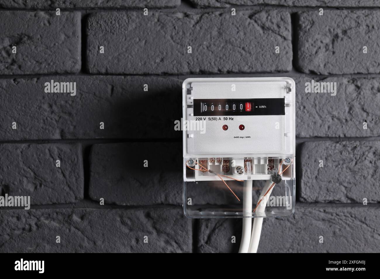 Electric meter on grey brick wall, space for text. Energy measuring ...
