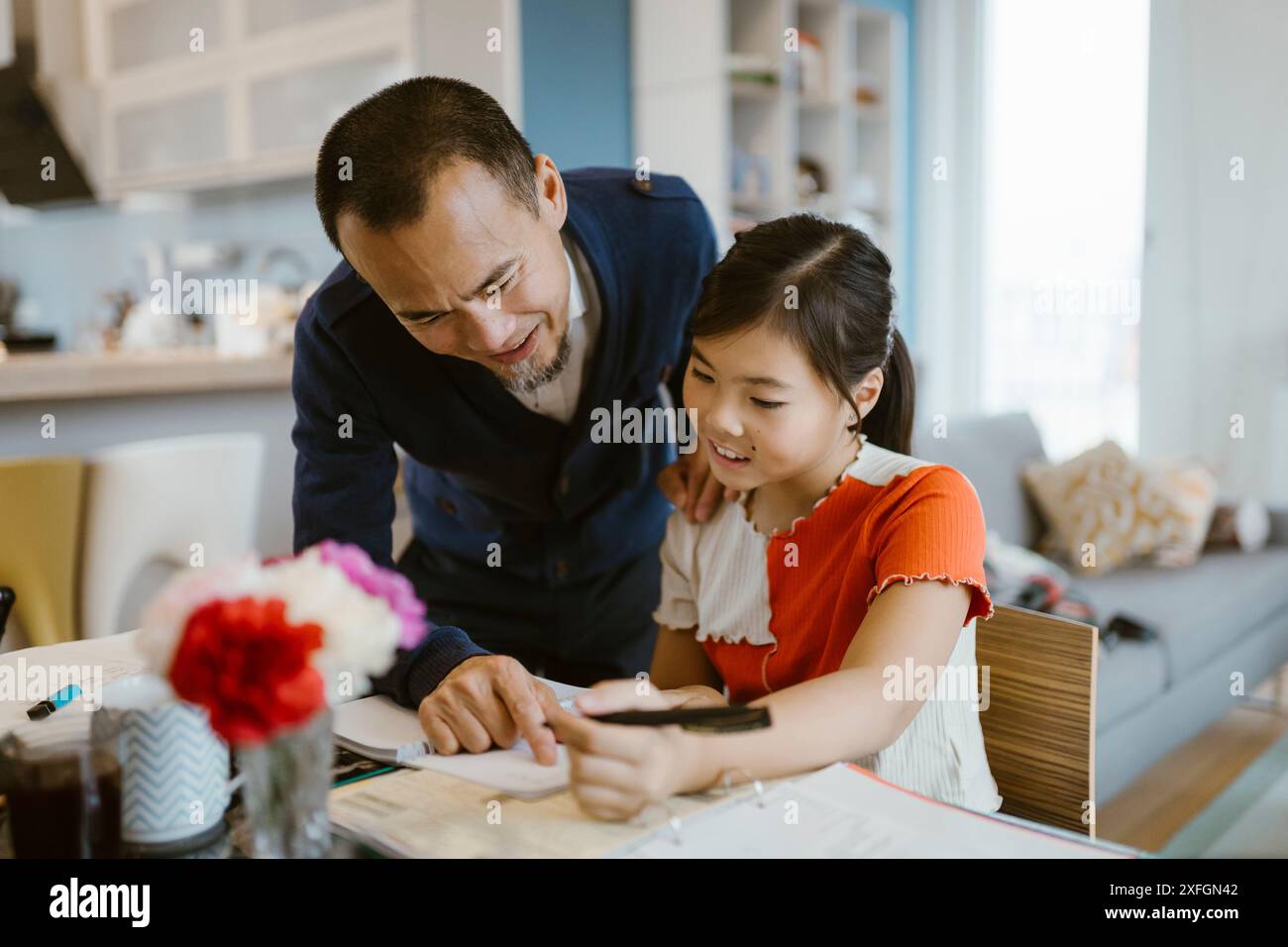 Smiling man assisting daughter doing homework Stock Photo - Alamy
