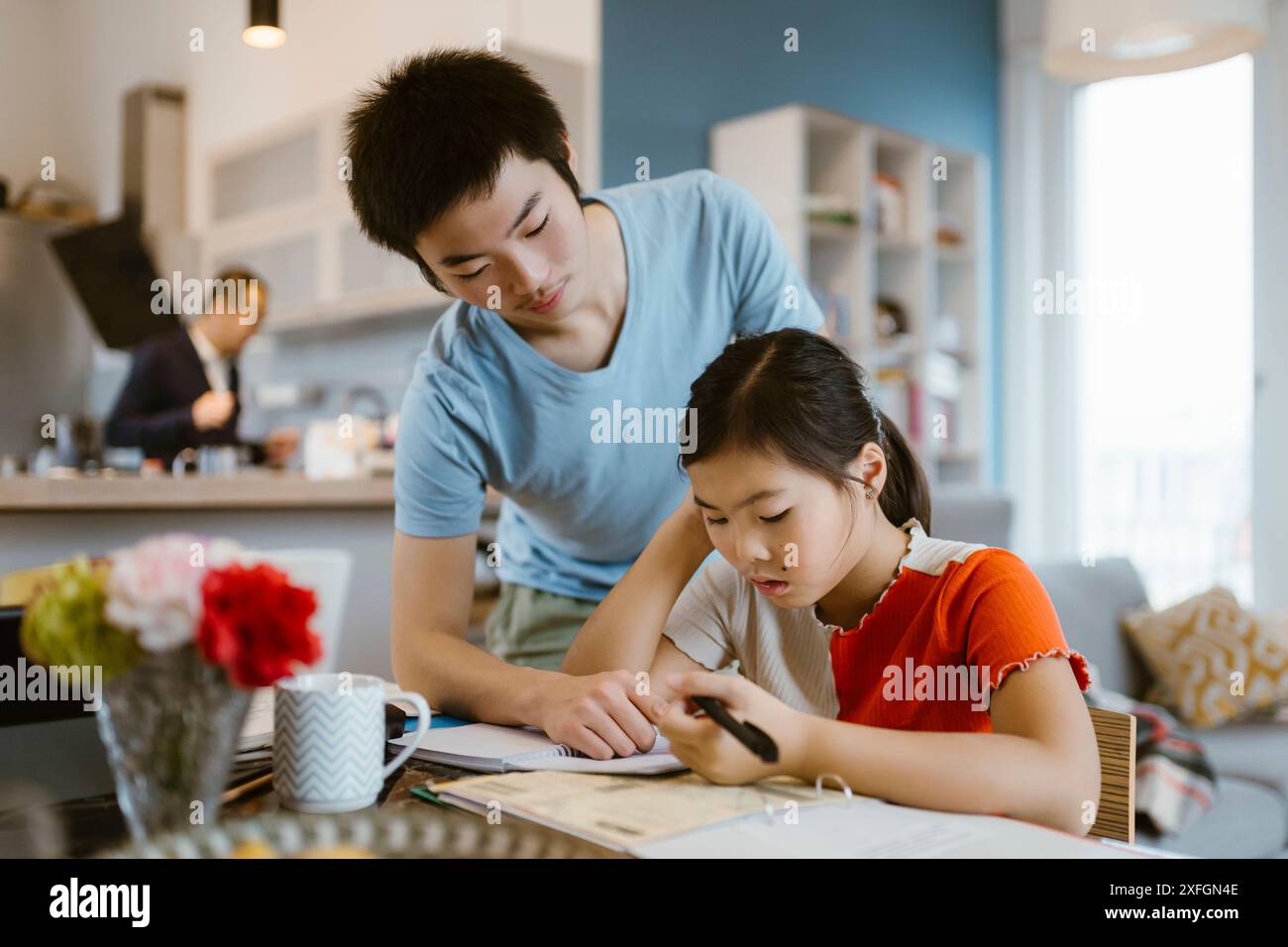 Brother helping sister while doing homework at home Stock Photo - Alamy