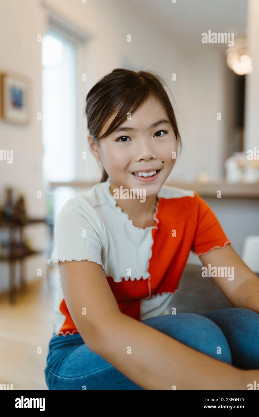 Portrait of smiling girl crouching at home Stock Photo - Alamy