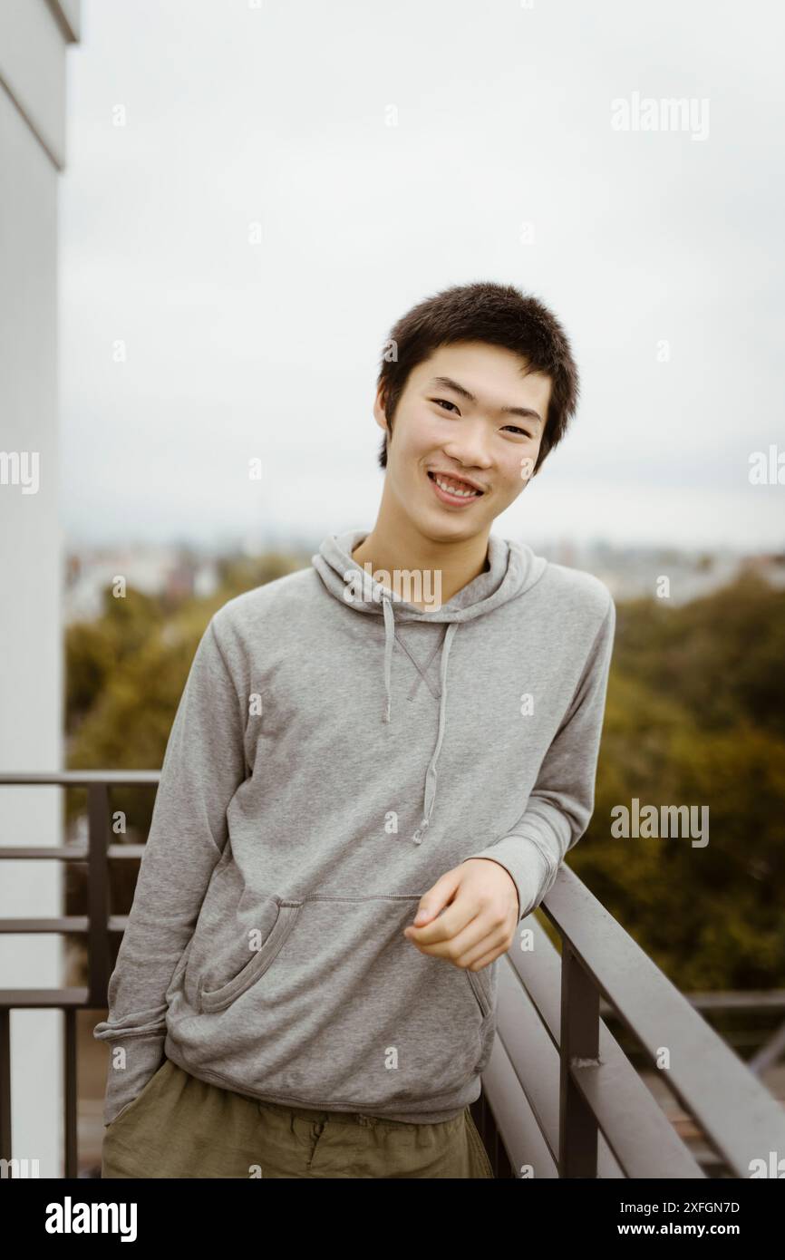 Portrait of smiling teenage boy leaning on railing in balcony Stock ...
