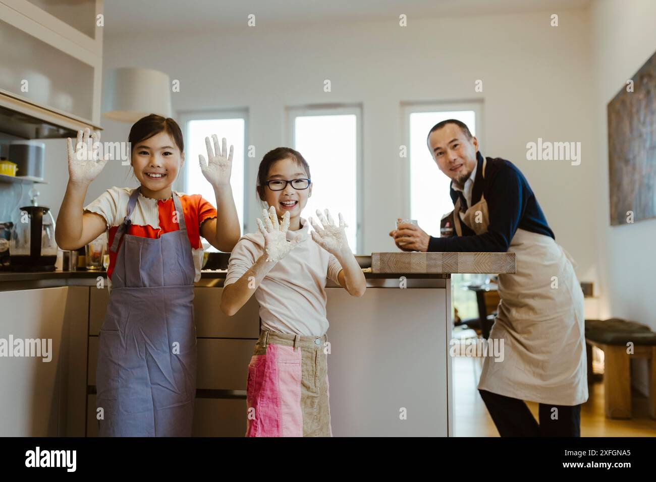 Smiling sisters showing messy hands while standing with father in ...