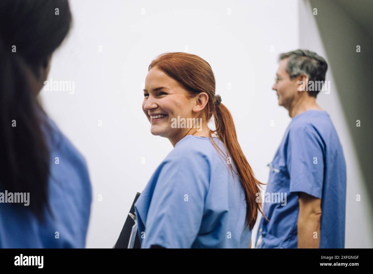 Smiling female medical trainee talking with coworker in hospital Stock ...