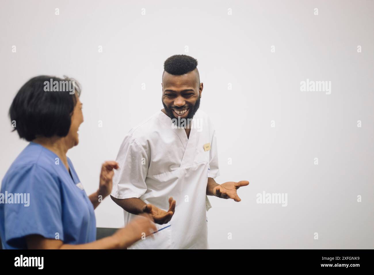 Happy male medical practitioner talking with senior female colleague ...