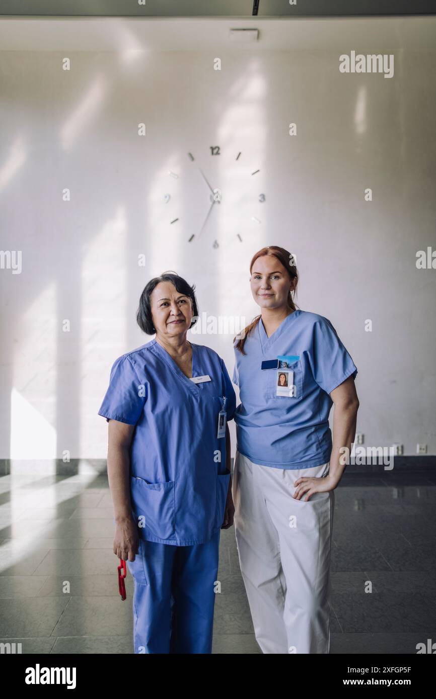 Portrait of senior female doctor standing with young trainee in front ...