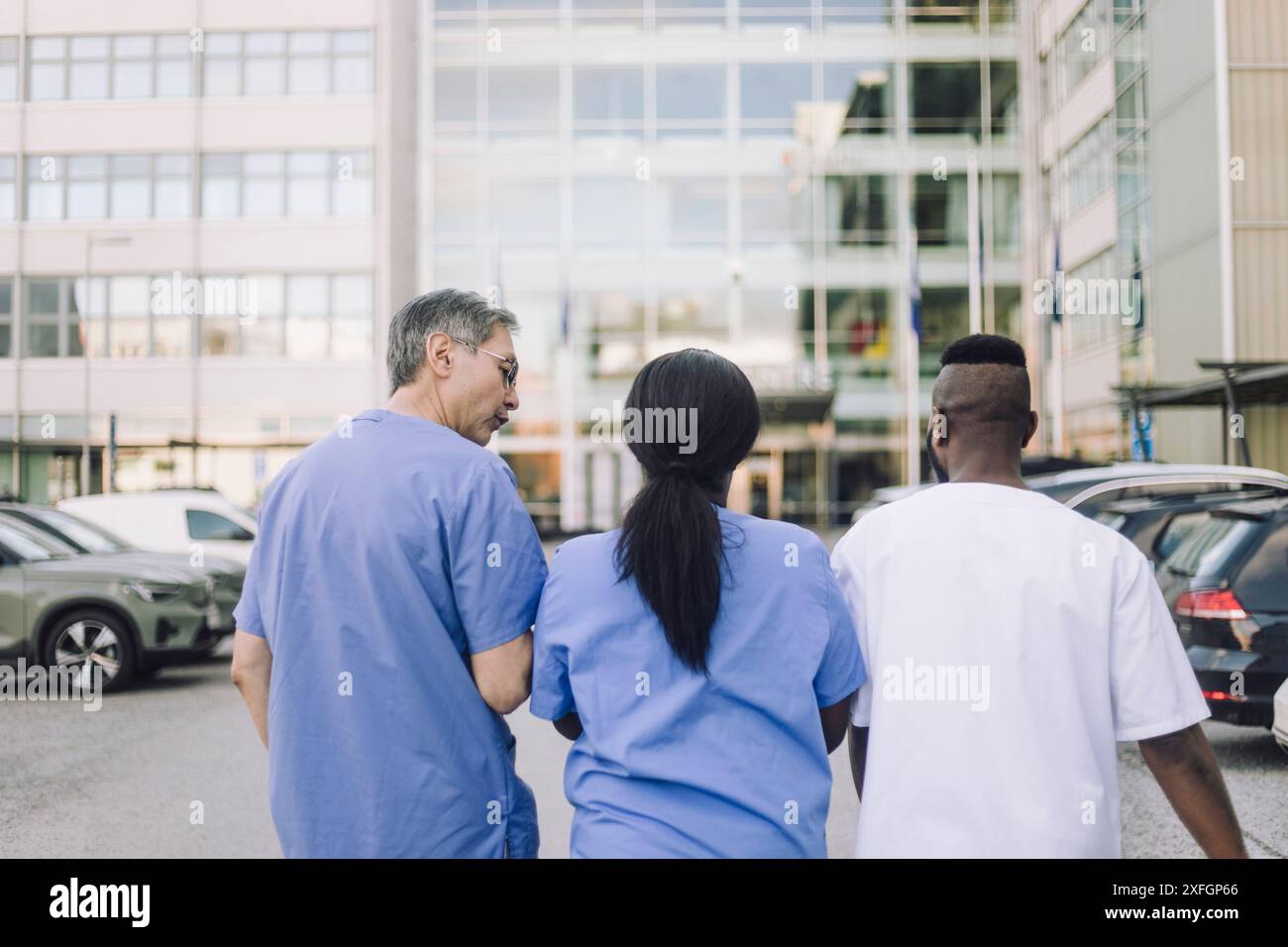 Rear view of male and female healthcare workers discussing while ...