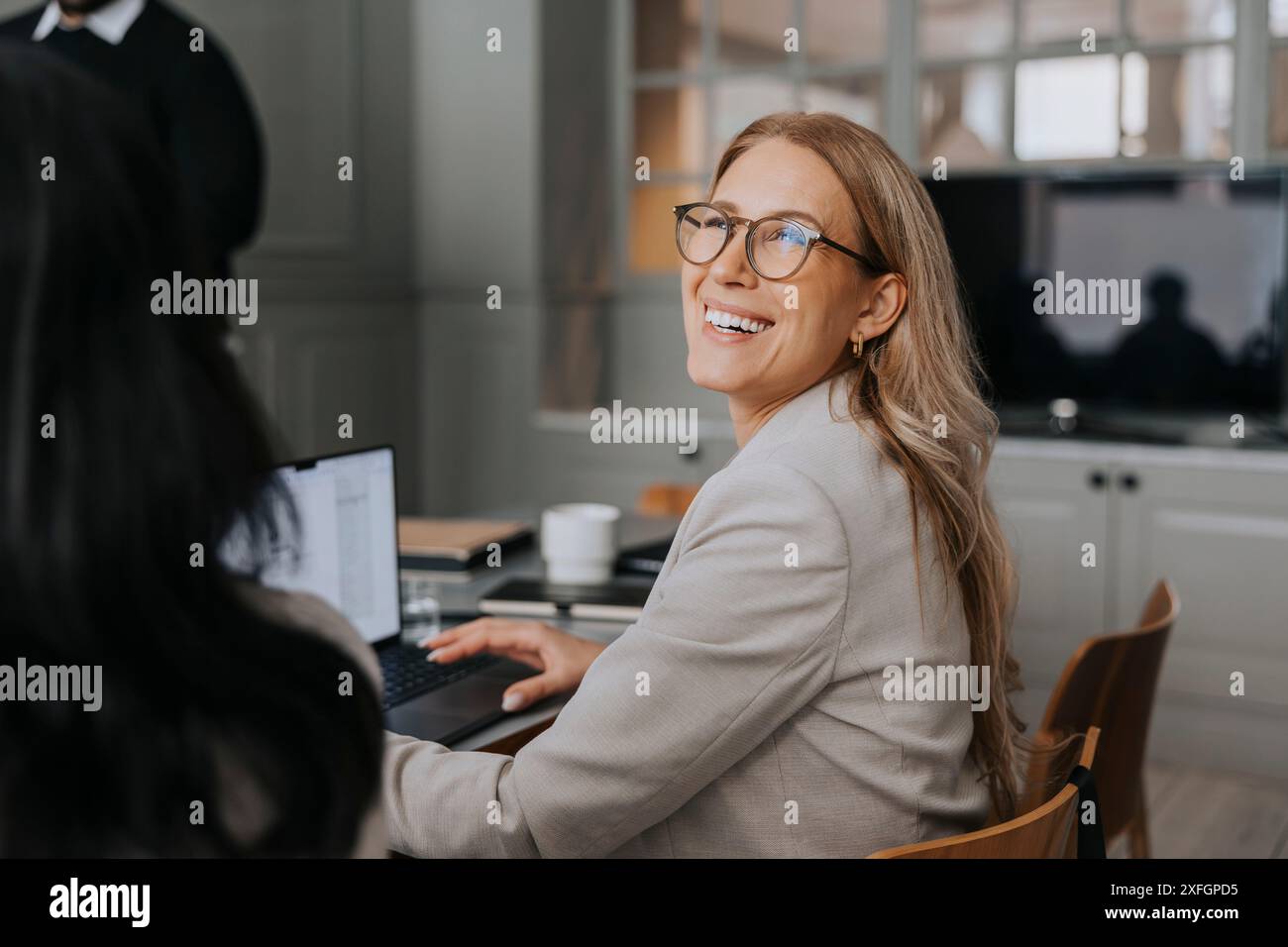 Happy businesswoman wearing eyeglasses sitting in office Stock Photo ...