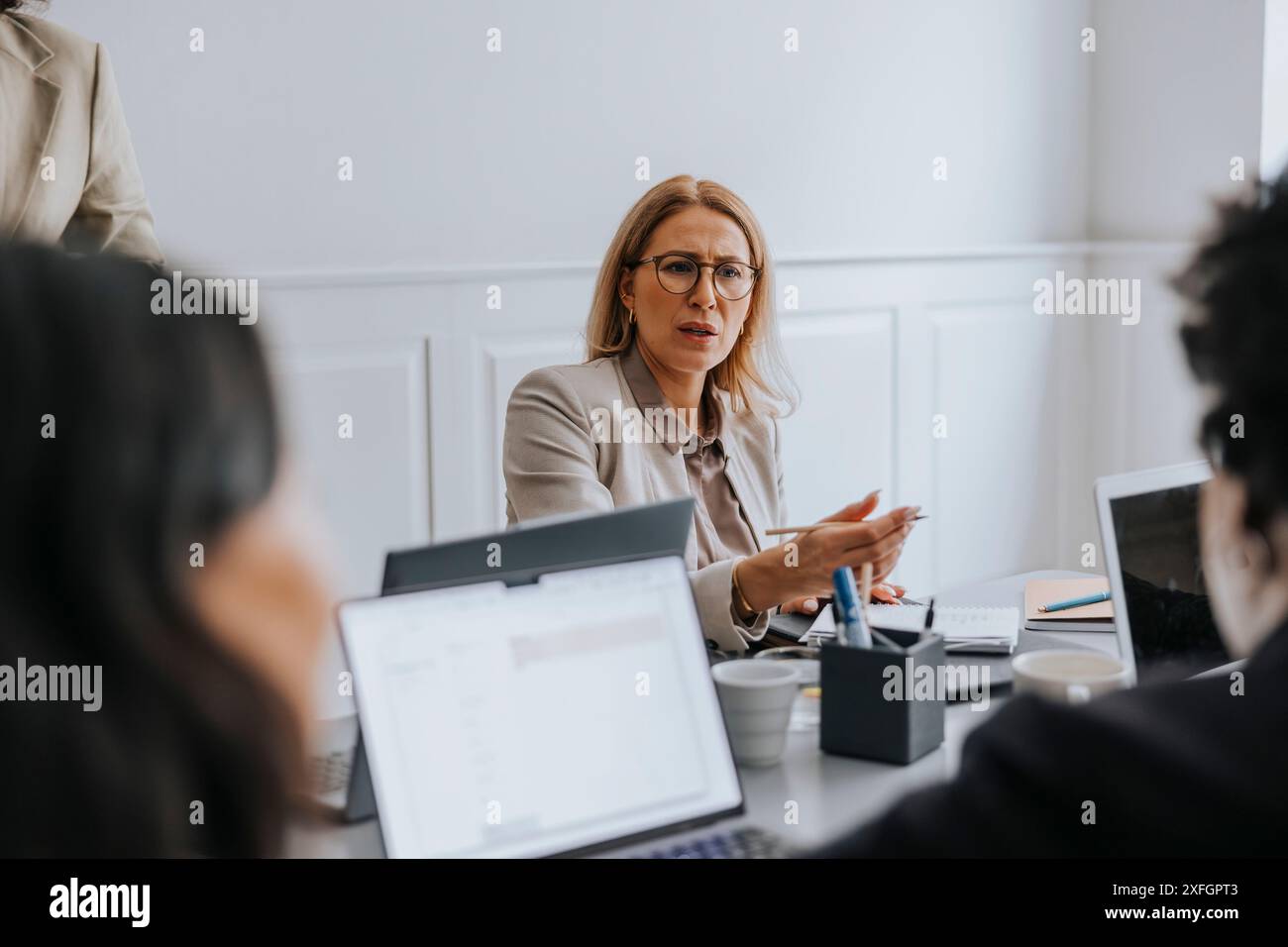 Confused female entrepreneur explaining ideas to coworkers while ...
