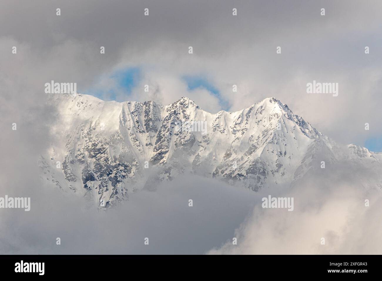Misty, cloudy snow capped mountain top in northern Canada, Yukon ...