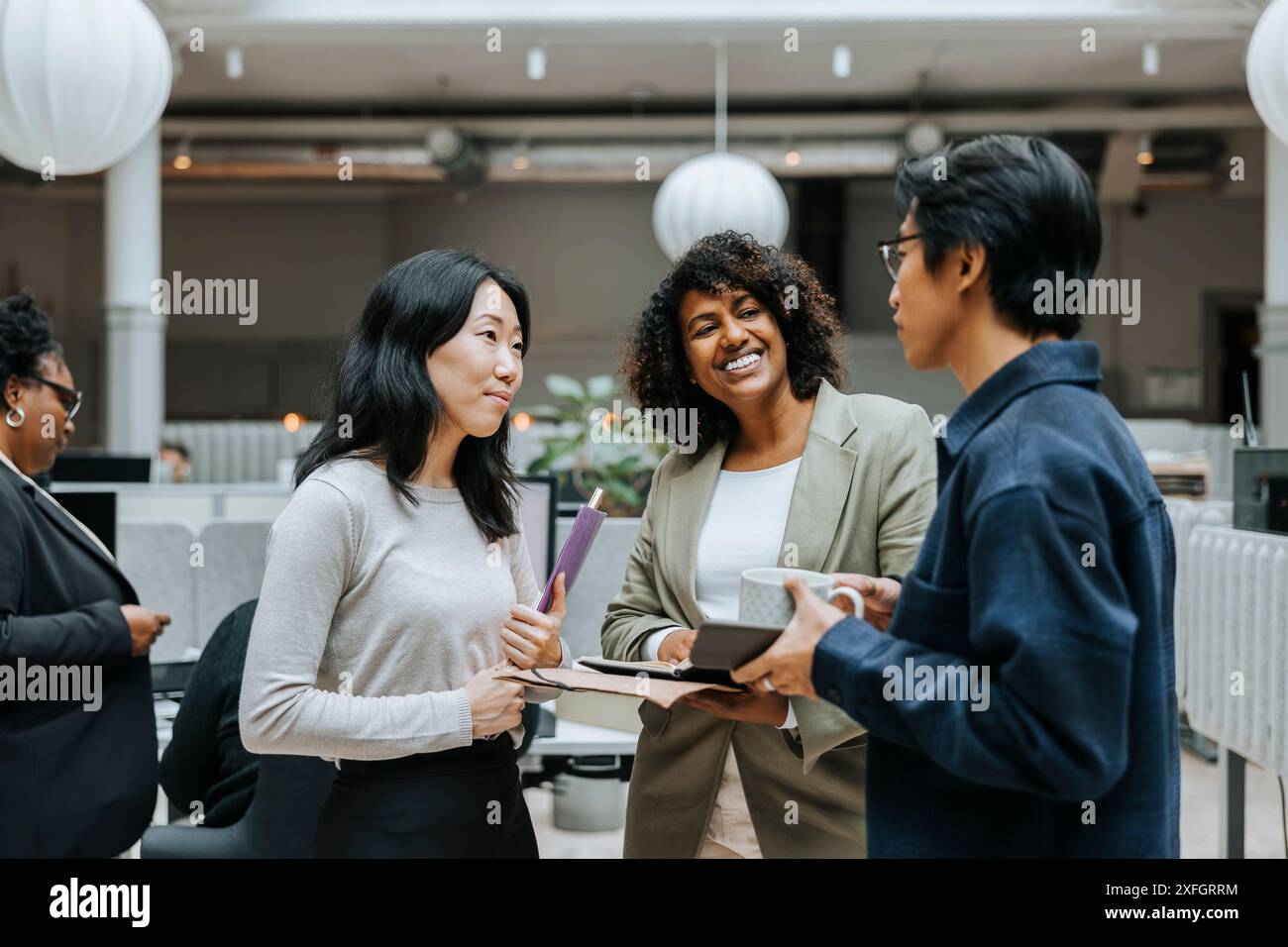 Multiracial male and female entrepreneurs discussing while standing at ...