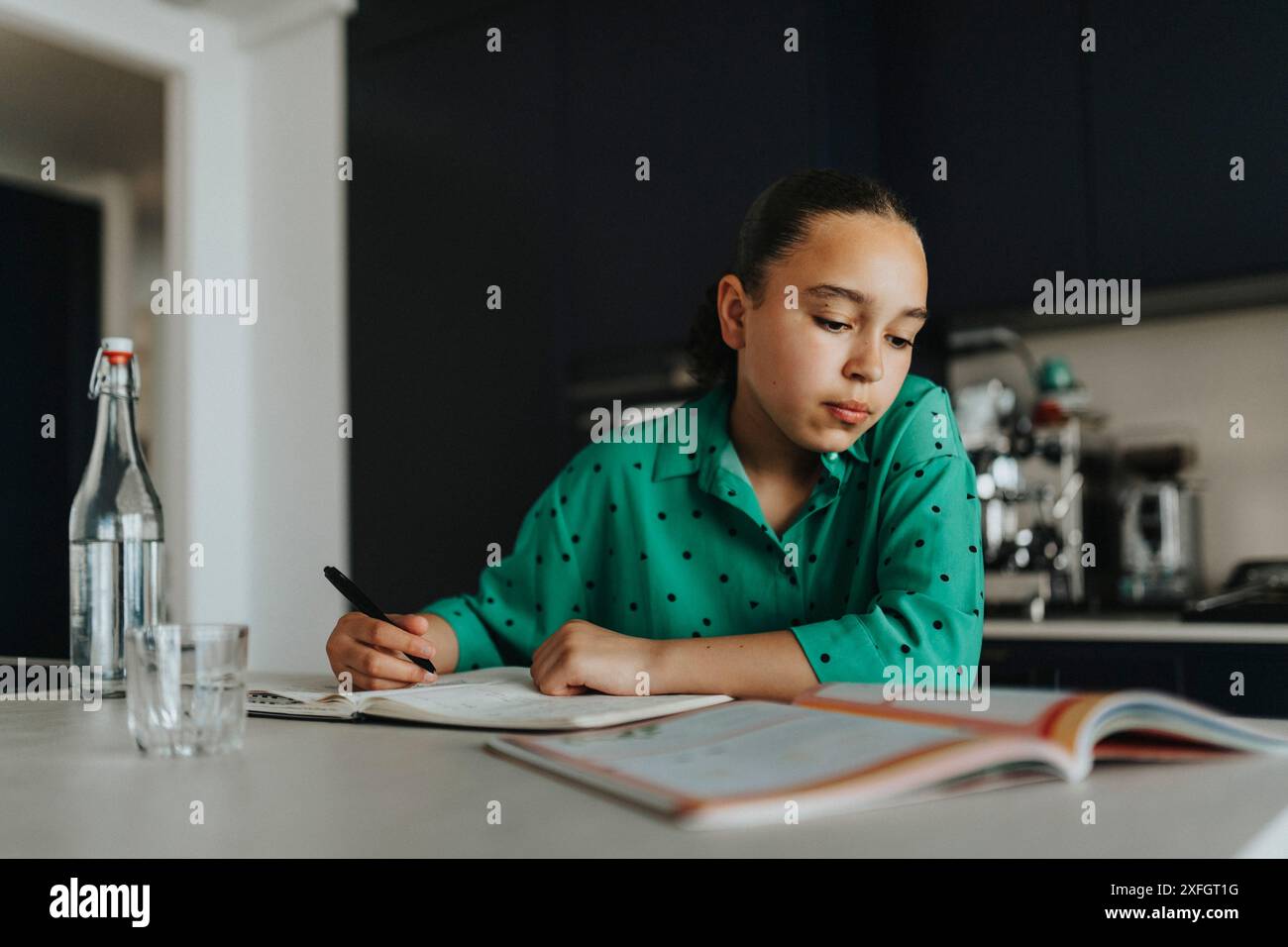 Focused girl reading while doing homework at home Stock Photo - Alamy