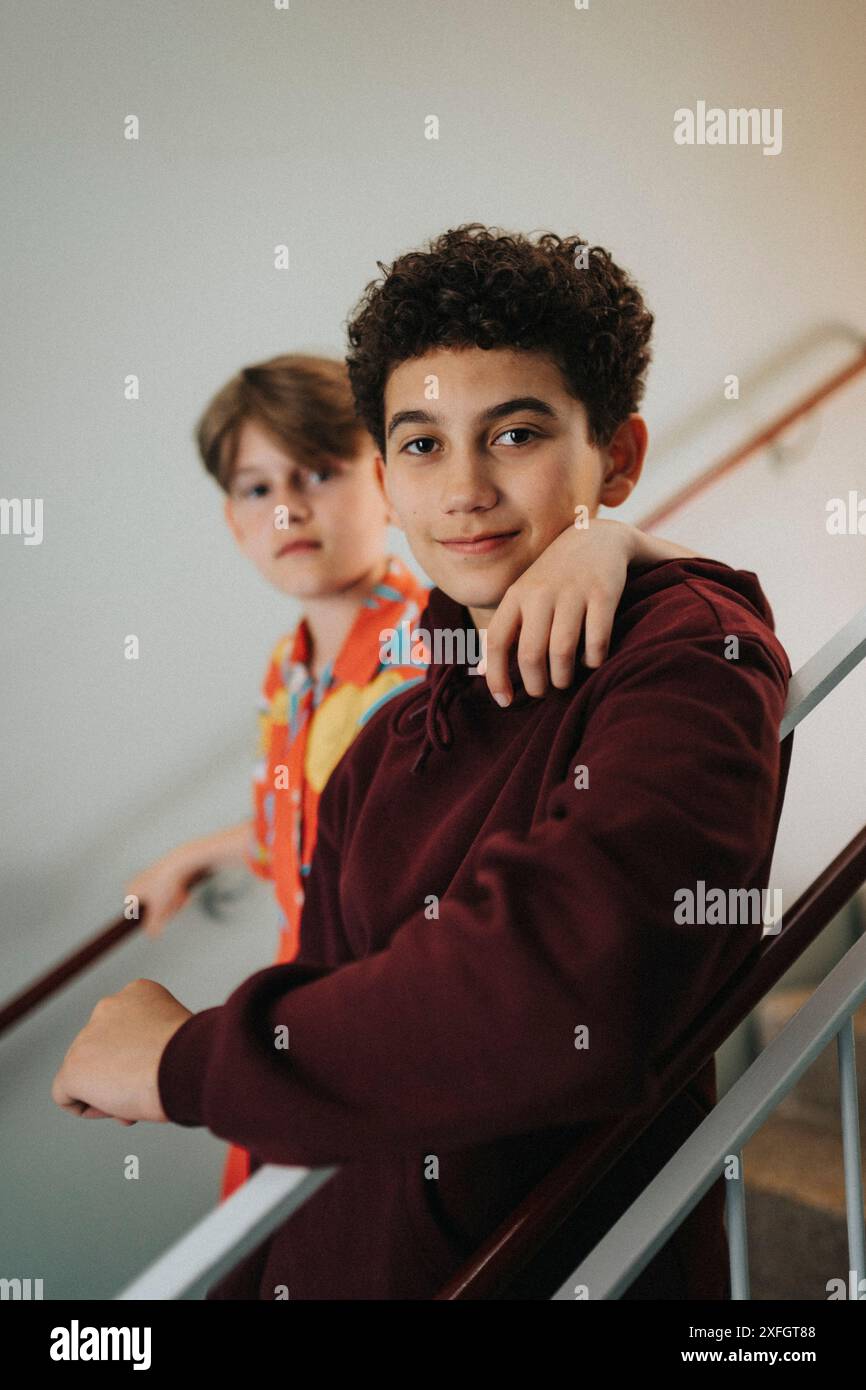 Portrait of boys moving down stairs with arm around at school Stock ...