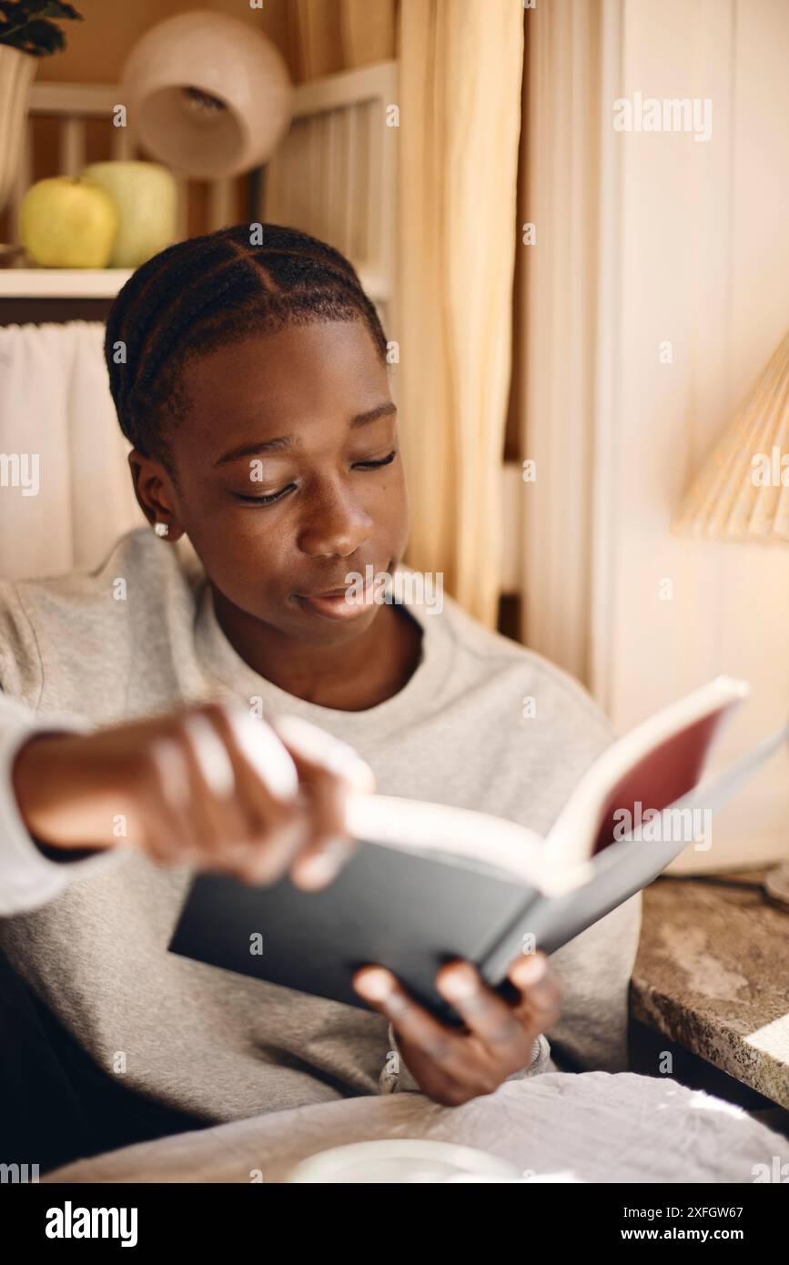 Teenage boy reading book while sitting at home Stock Photo - Alamy