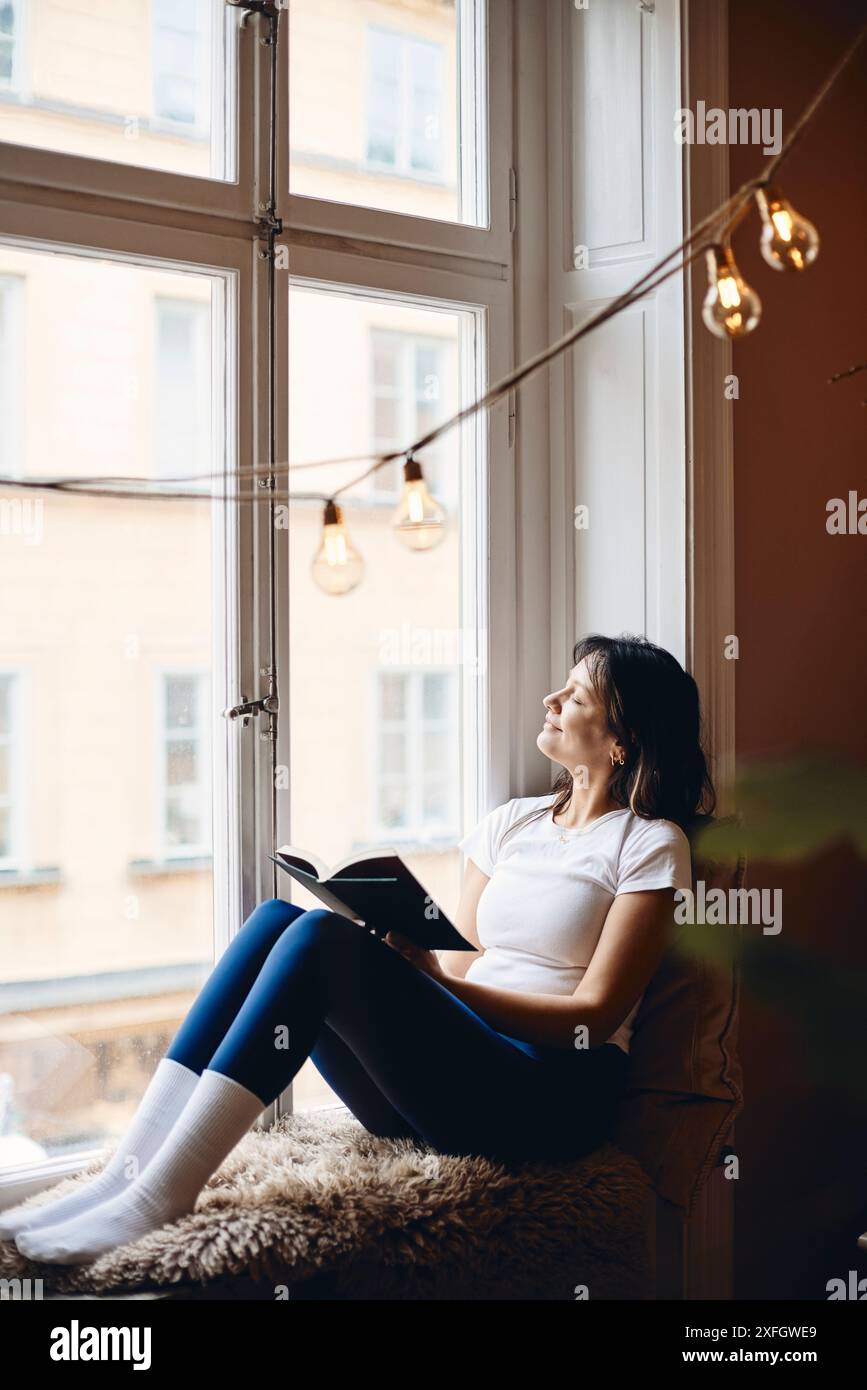 Young woman sitting window home hi-res stock photography and images - Alamy
