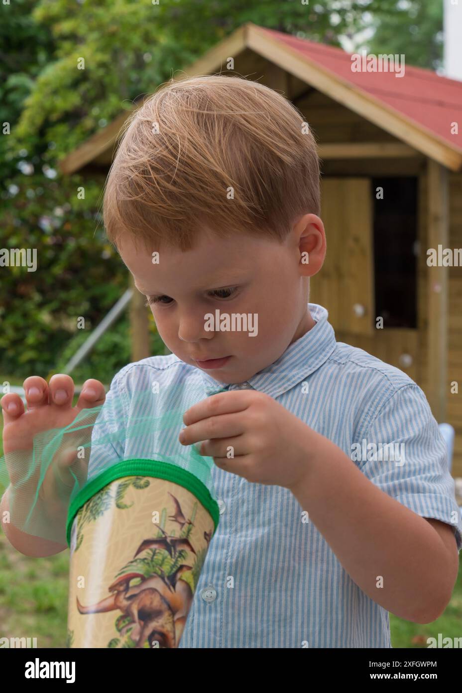 Portrait of a little boy. Opens a candy cone with interest. Joy ...