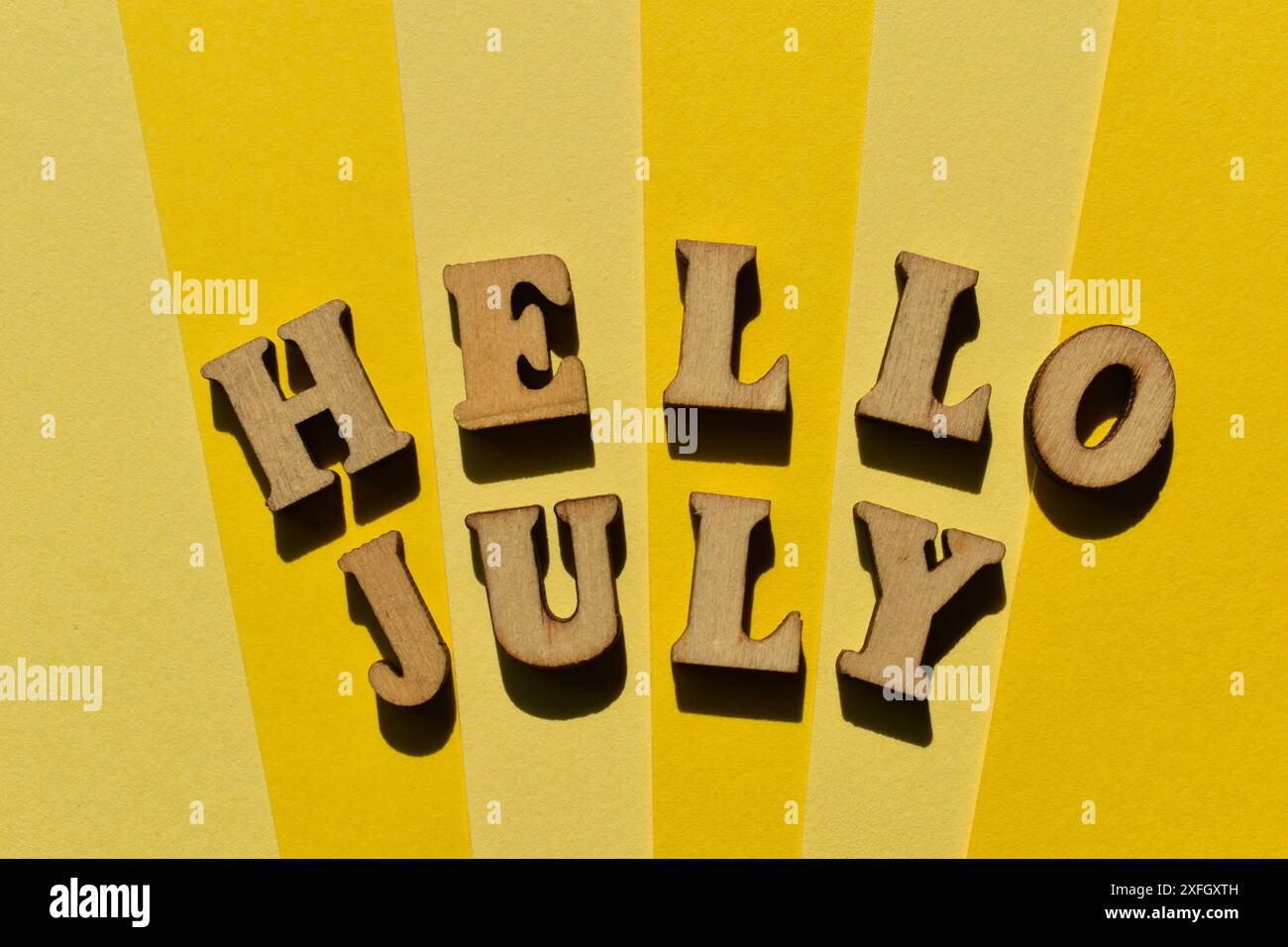 Hello July, words in wooden alphabet letters isolated on yellow ...