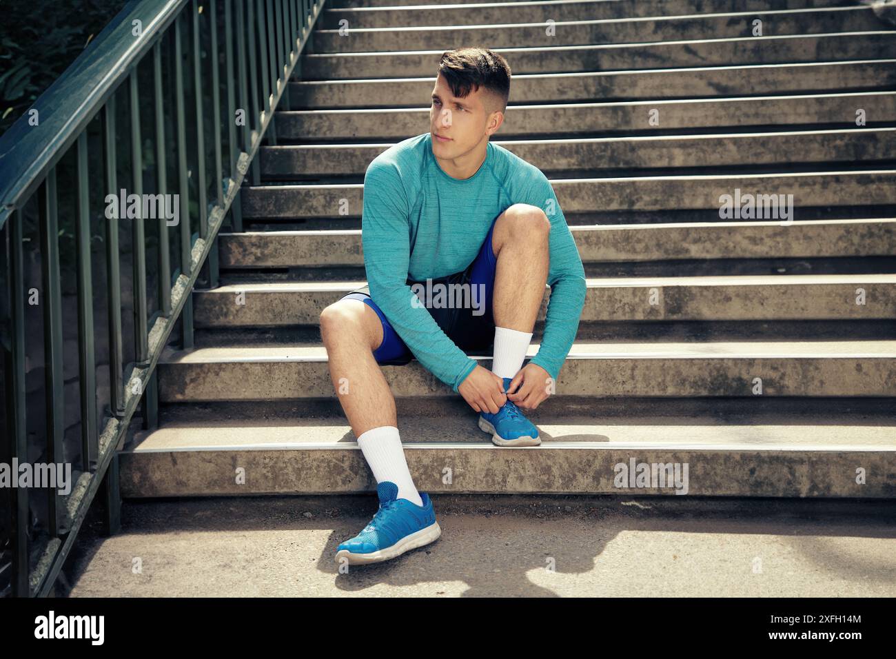 man tie shoe and get ready for sport while sit on step of stair look to ...