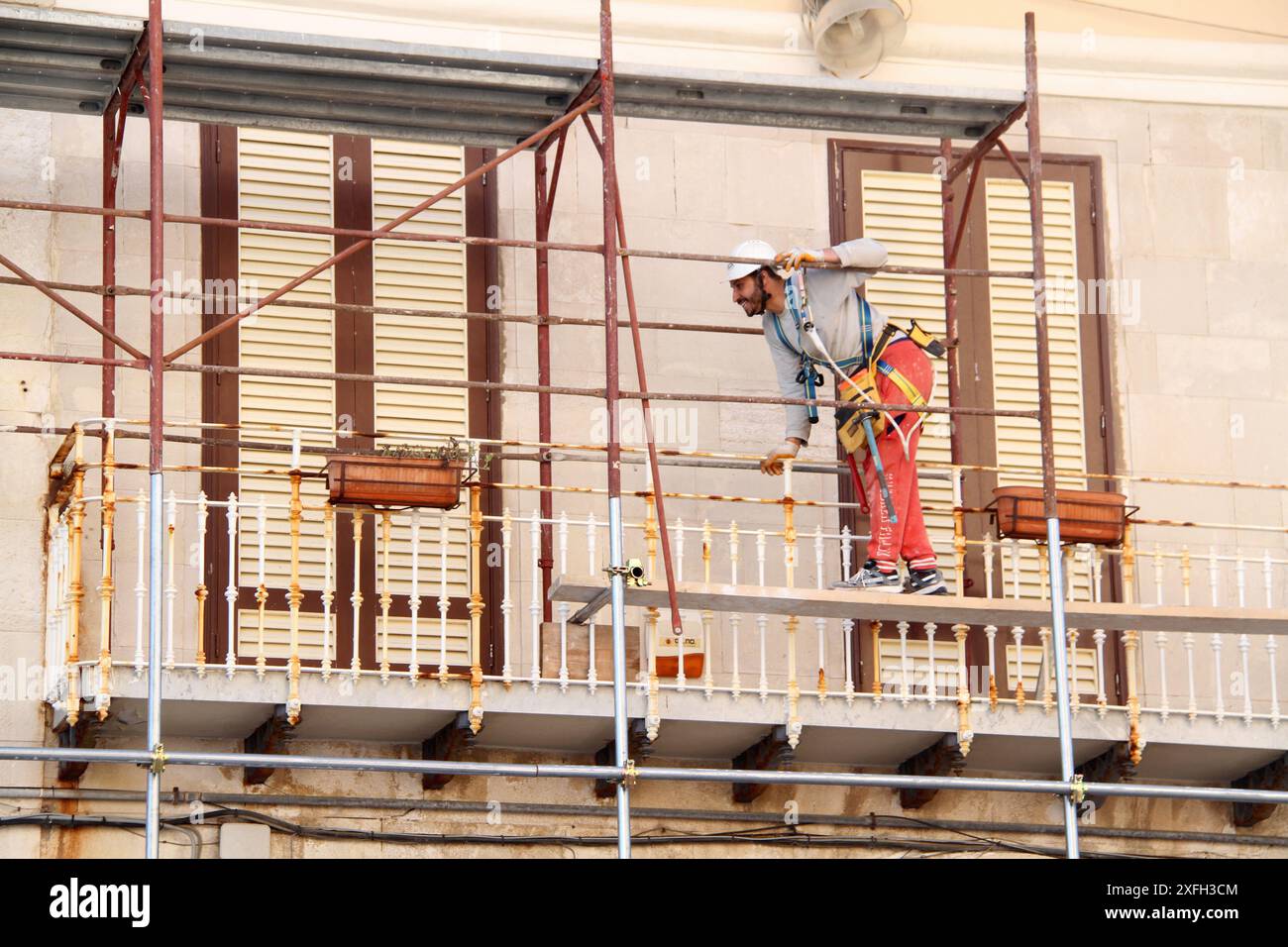 Worker on a scaffold renovating the exterior of a building in the ...