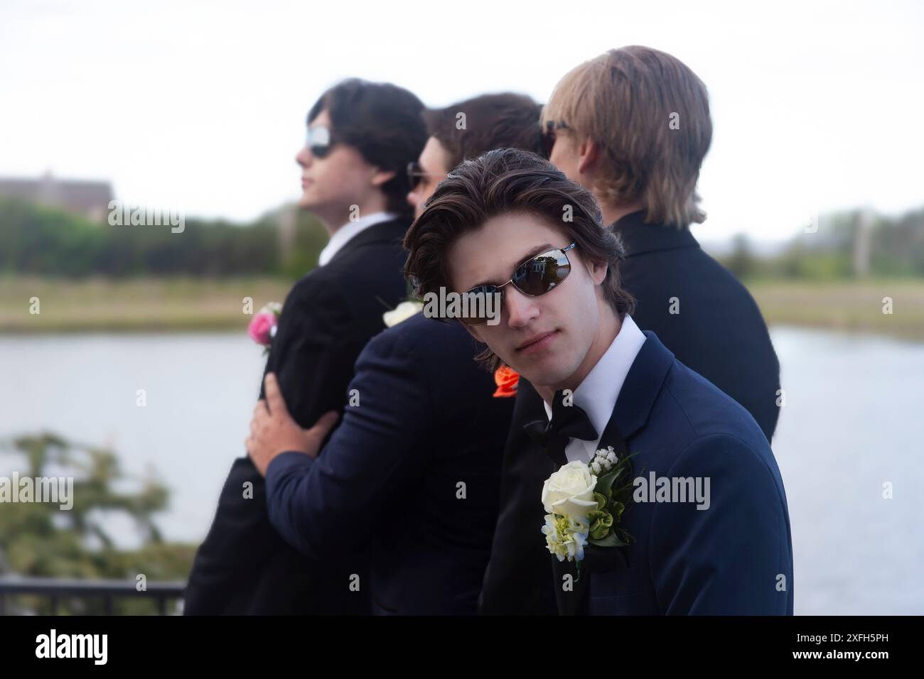 Young boy in sunglasses and suit facing camera with three friends, also ...