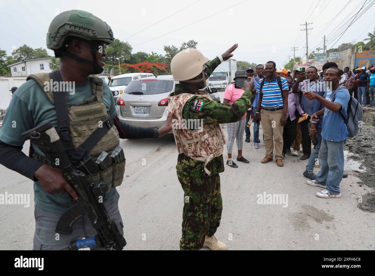 A Kenyan police officer takes candid photos of a group of Haitians ...