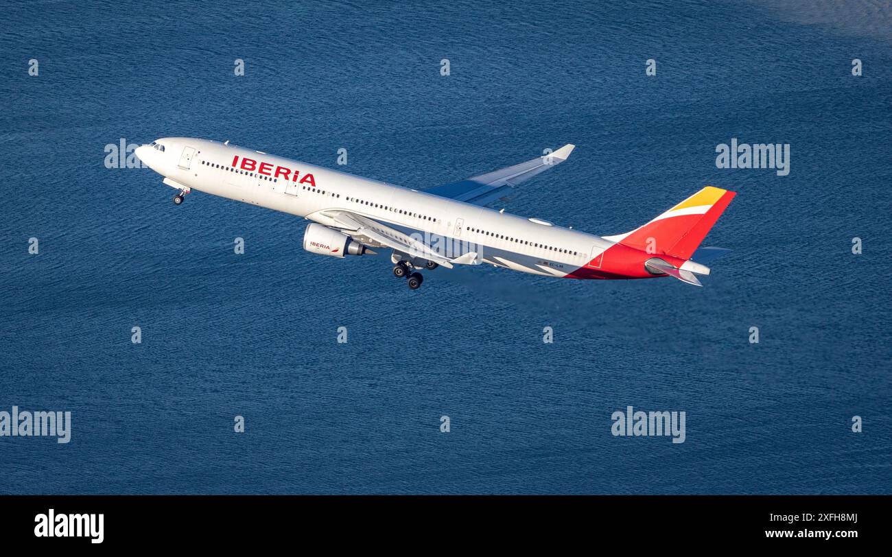 Iberia aircraft in flight over a body of water, showcasing the airline ...