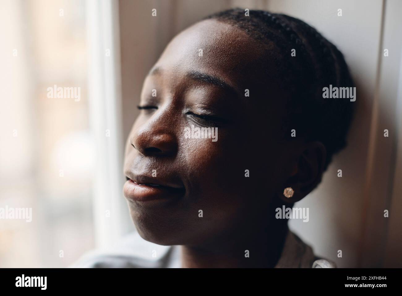 Close-up of teenage boy with eyes closed near window at home Stock ...