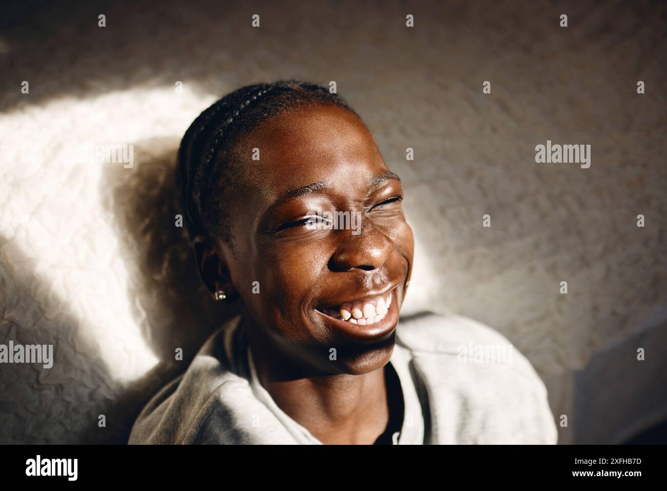 Happy teenage boy winking while sitting near bed at home Stock Photo ...