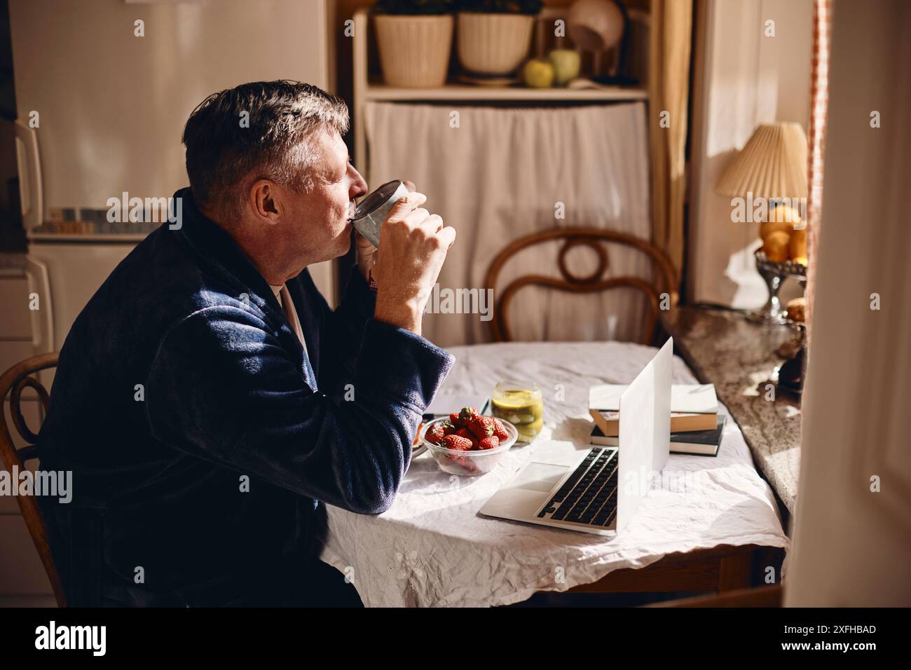 Side view of man drinking coffee while sitting at dining table with ...