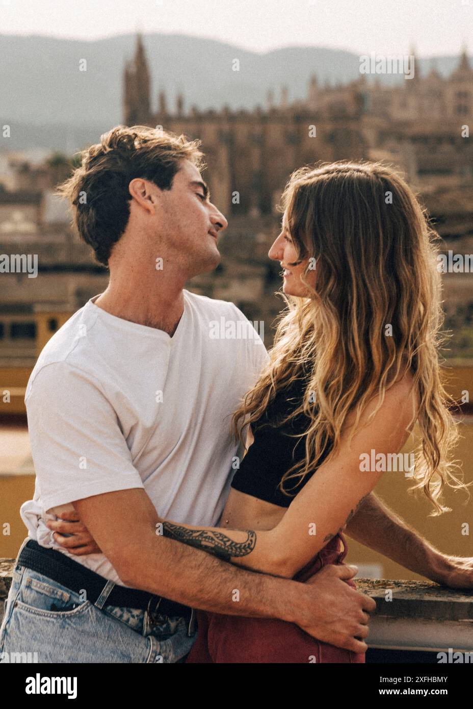 Romantic couple looking at each other standing near wall on rooftop ...