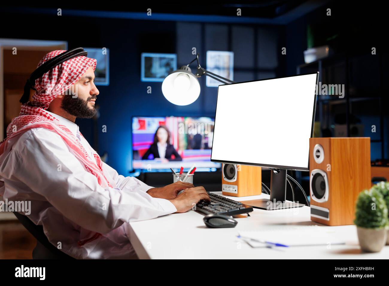 Islamic guy sits at his home office table, his desktop computer monitor ...