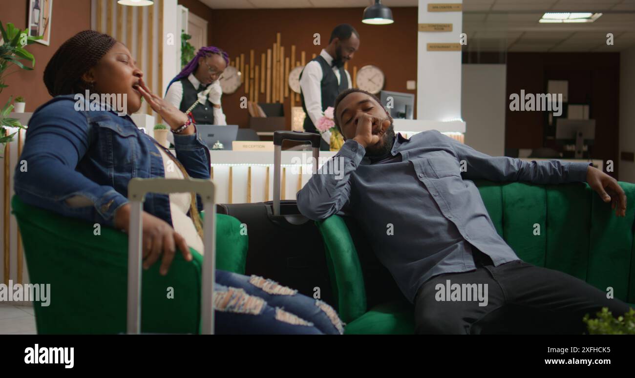 Exhausted people resting in hotel lobby, waiting for registration and ...