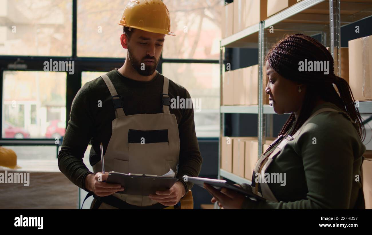 Dolly in shot of experts in warehouse inputing updated products info on ...