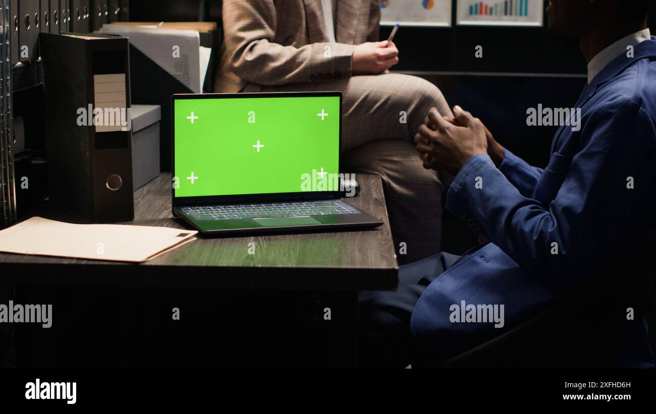 Modern laptop with blank green screen positioned on desk in police ...