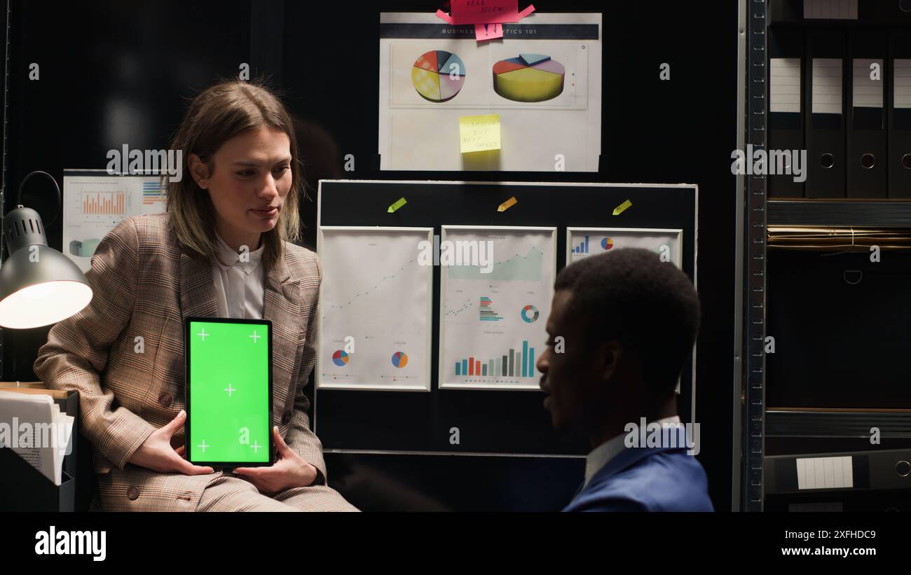 Female investigator grasps device with greenscreen to present mockup ...