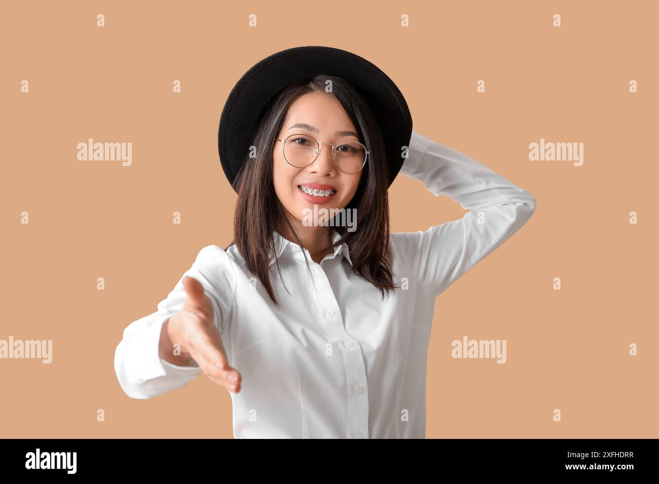 Beautiful young Asian woman extending hand for handshake on beige ...