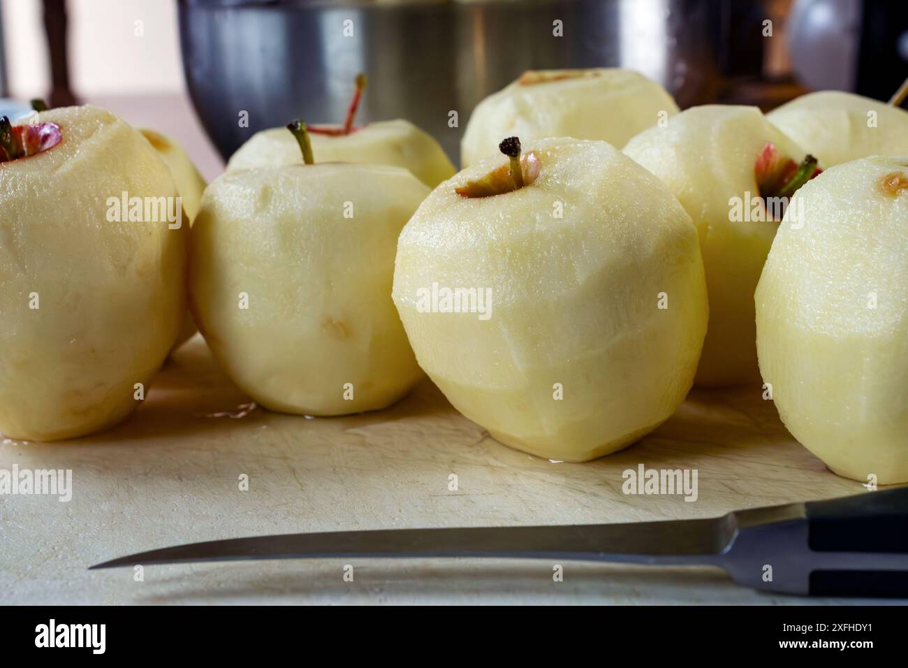 Gala apples peeled sitting on a white cutting board with a knife ...