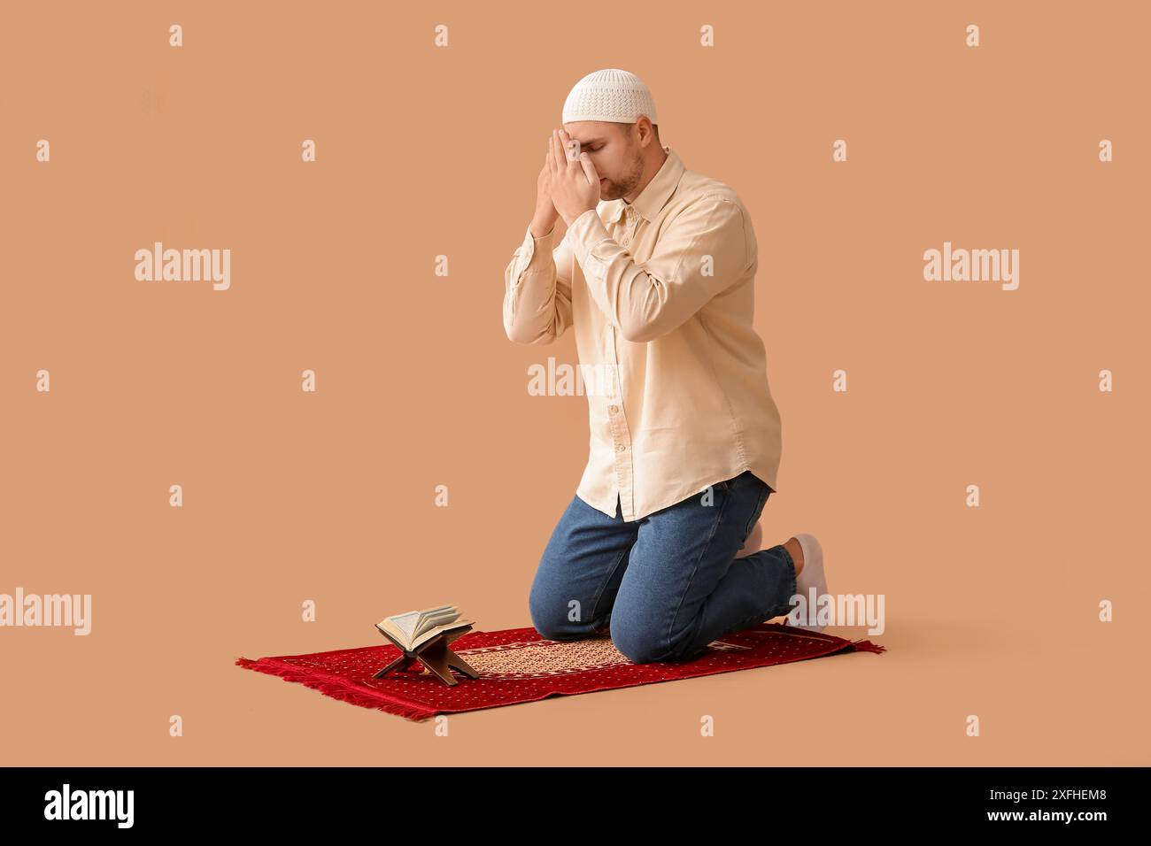 Young Muslim man with prayer mat and Koran praying on beige background ...