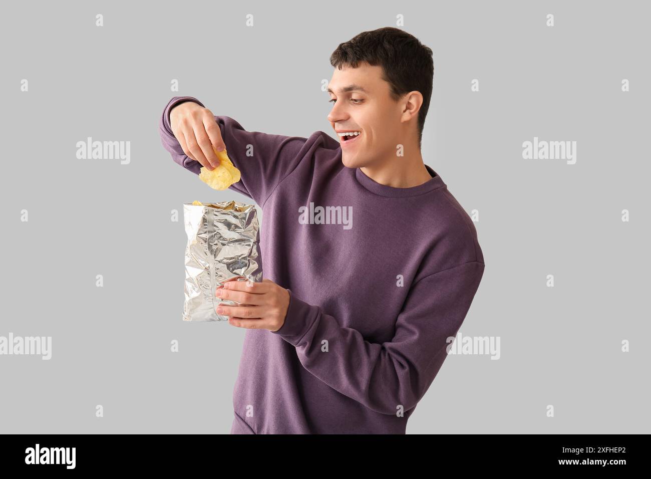 Young man with potato chips on light background Stock Photo - Alamy